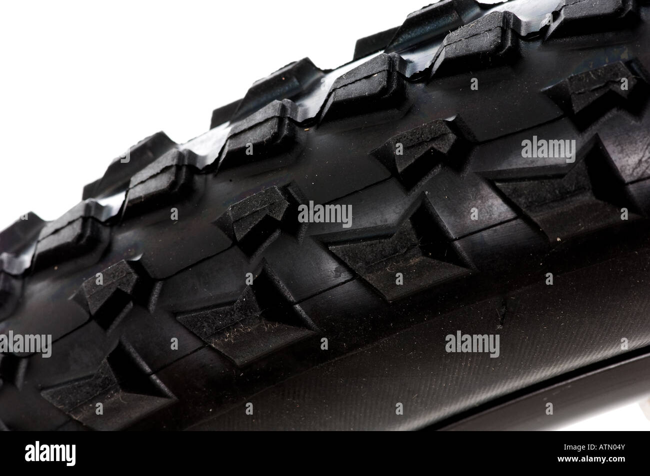 Closeup of the tread on a black mountain bike tyre seen against a white ...