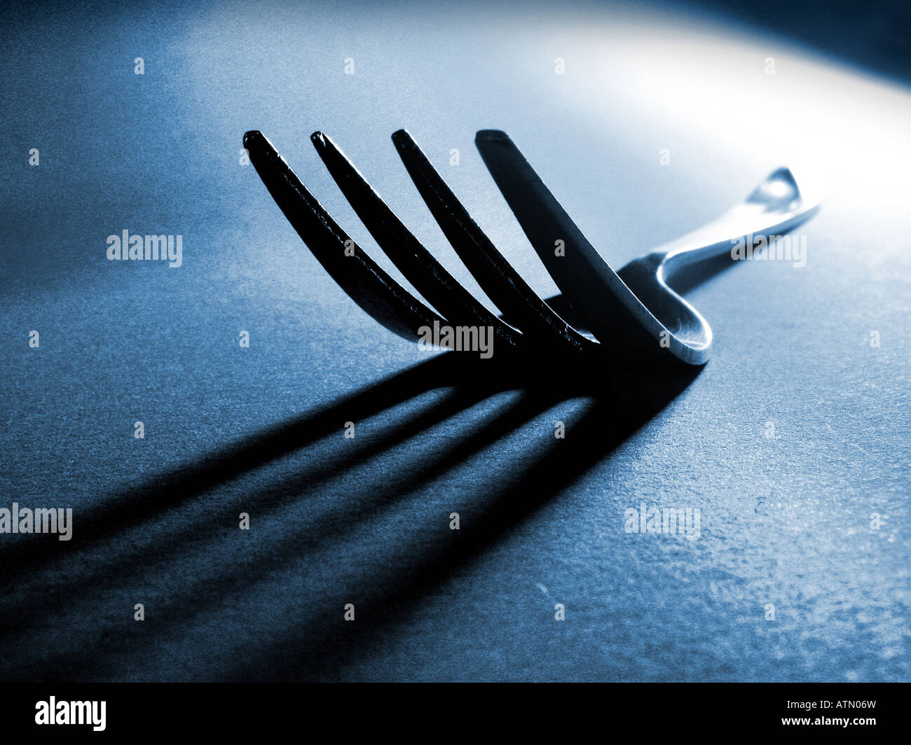 Fork on textured background with long shadow Stock Photo - Alamy