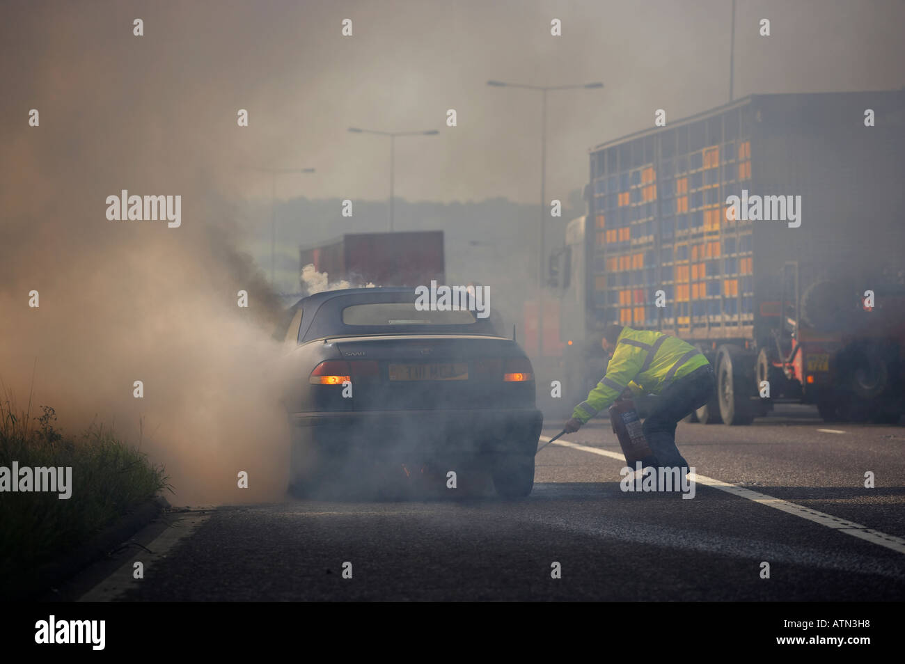 EMERGENCY SERVICES USING FIRE EXTINGUISHER ON BURNING CAR ON MOTORWAY ...