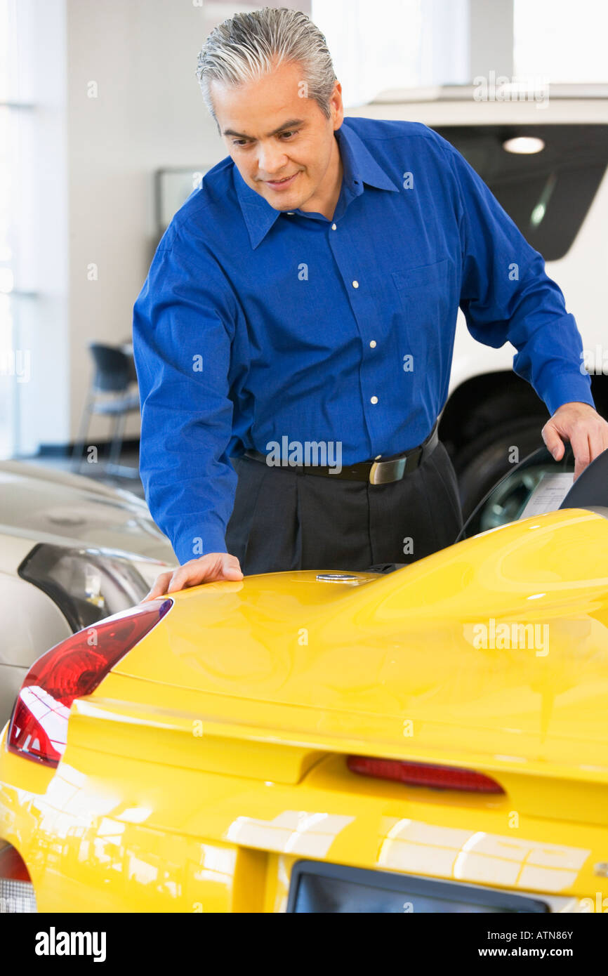Hispanic car salesman looking at new car Stock Photo - Alamy