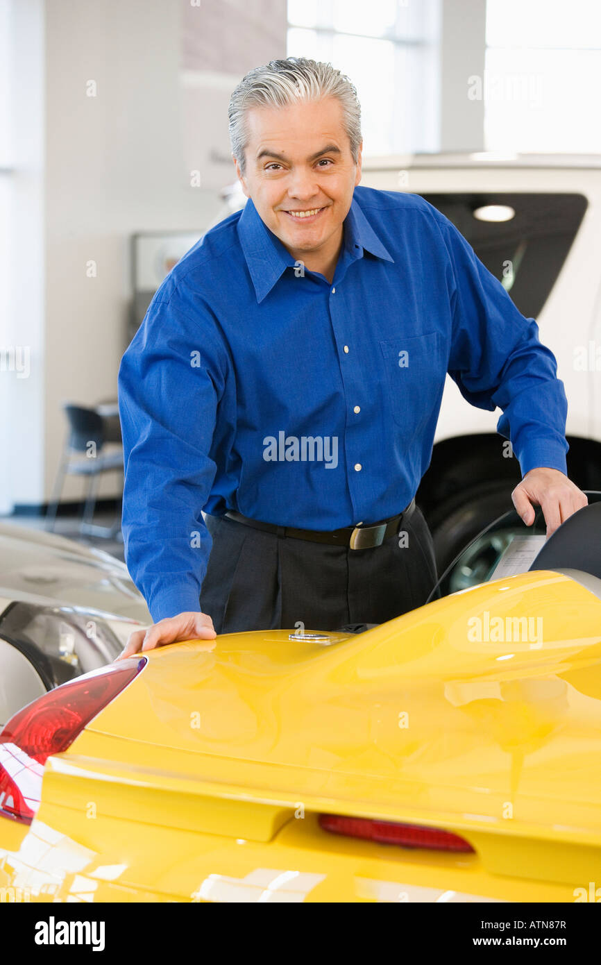 Hispanic car salesman looking at new car Stock Photo - Alamy