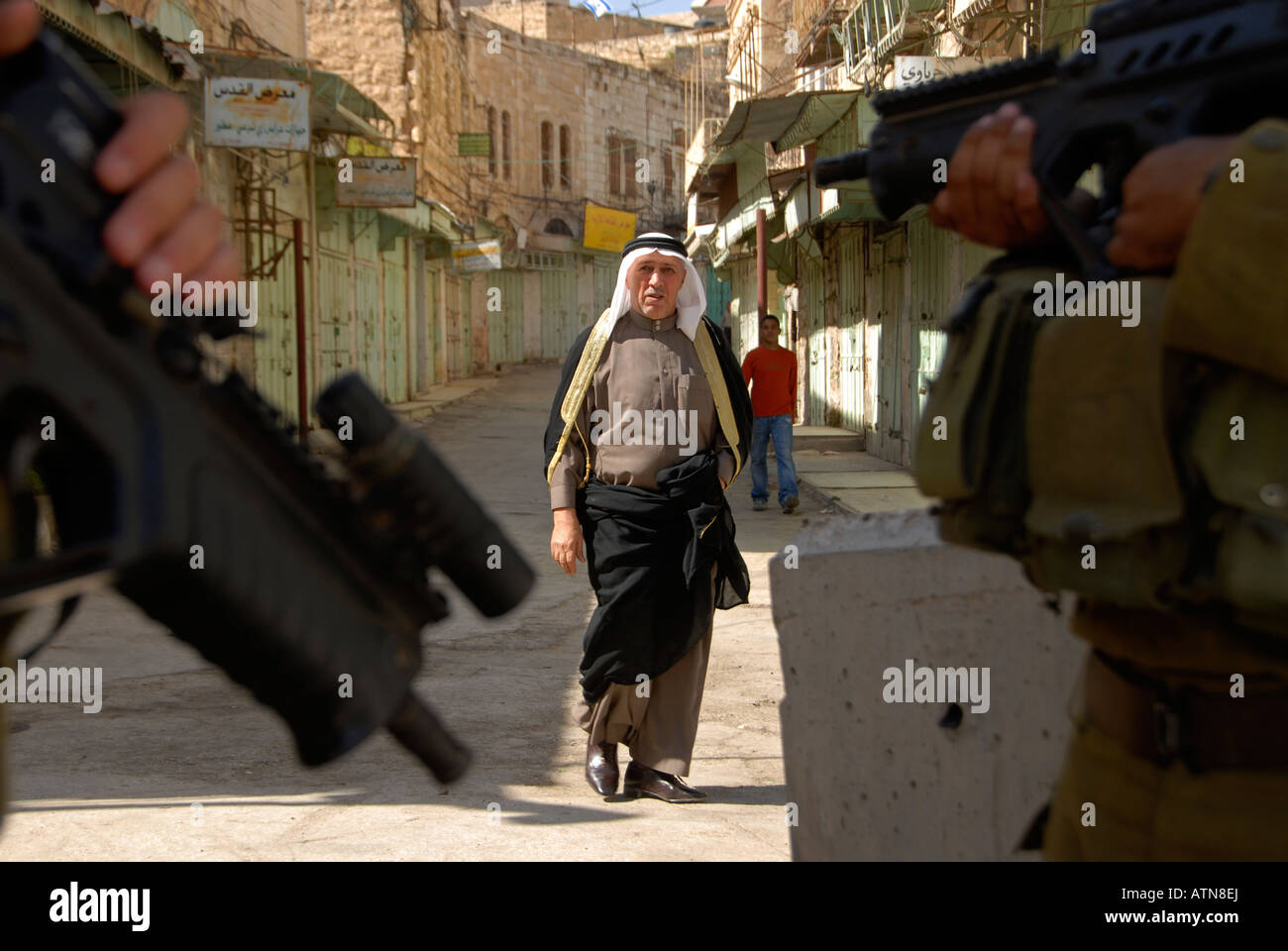 Armed Israeli soldiers stand guard as Palestinians pass by in the ...