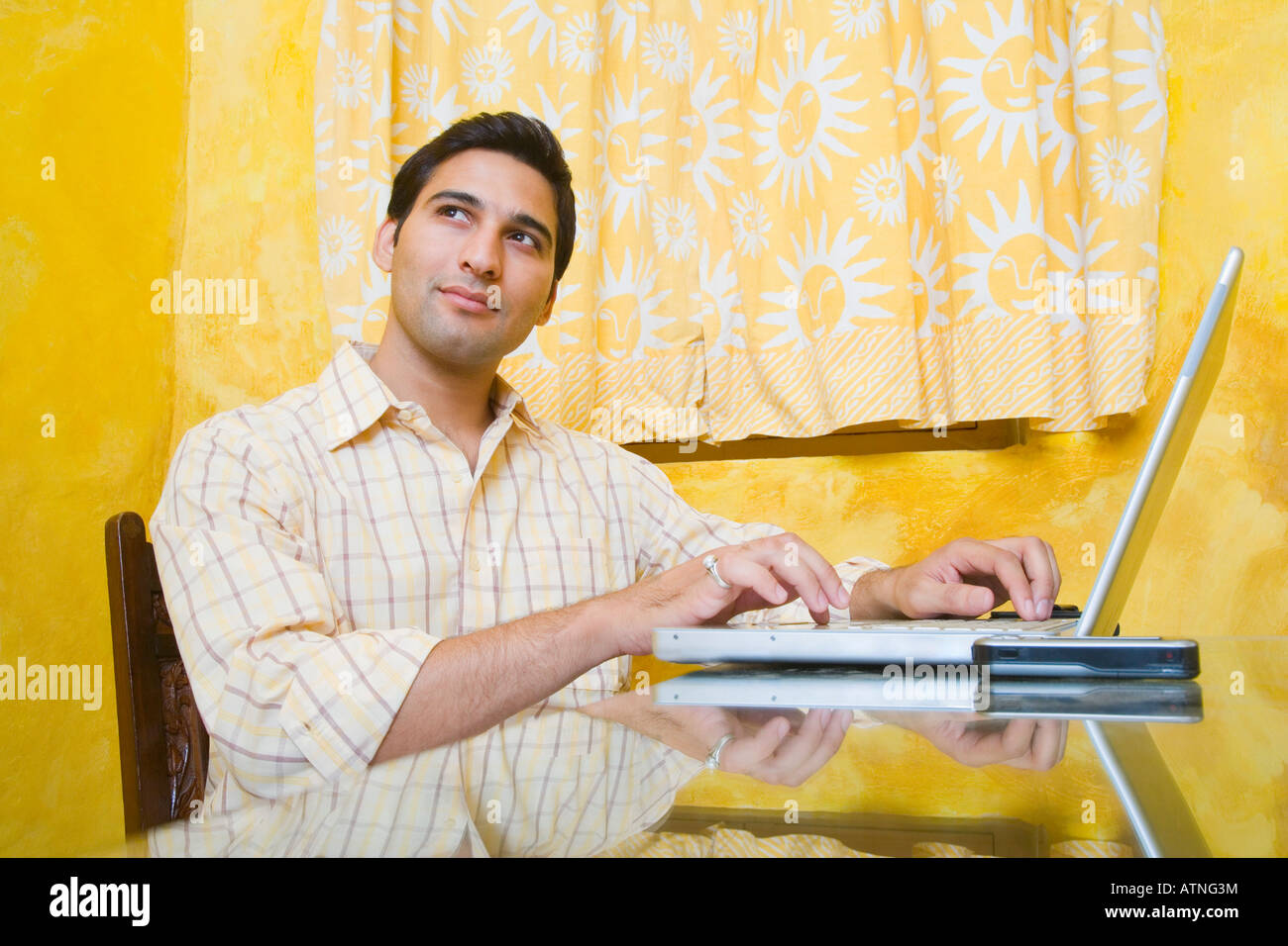 Young man using a laptop and thinking Stock Photo - Alamy