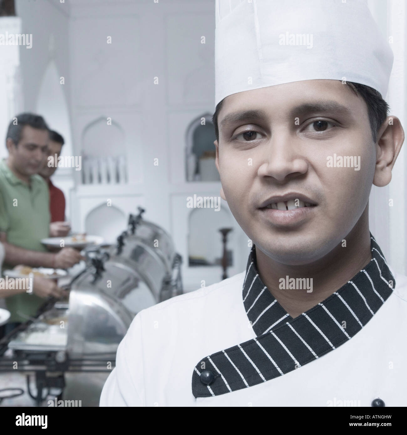 Portrait of a chef with two mid adult men having food behind him Stock ...