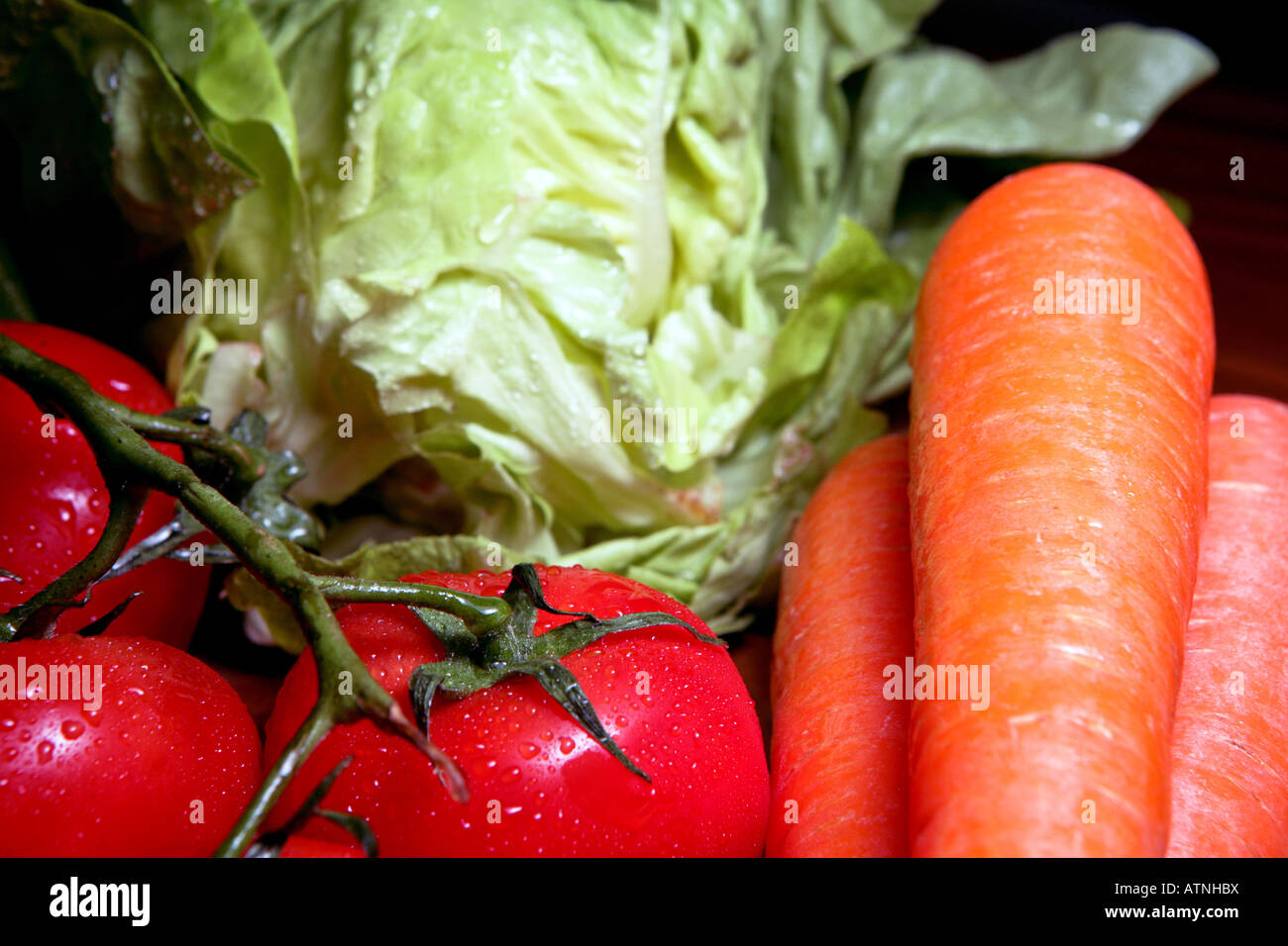 A close-up of bunch of vegetables carrots, a cluster tomatoes and green ...