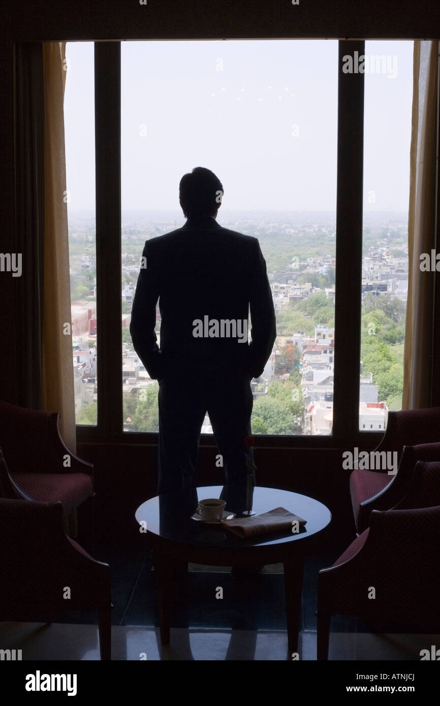 Rear view of a businessman looking through a window Stock Photo - Alamy