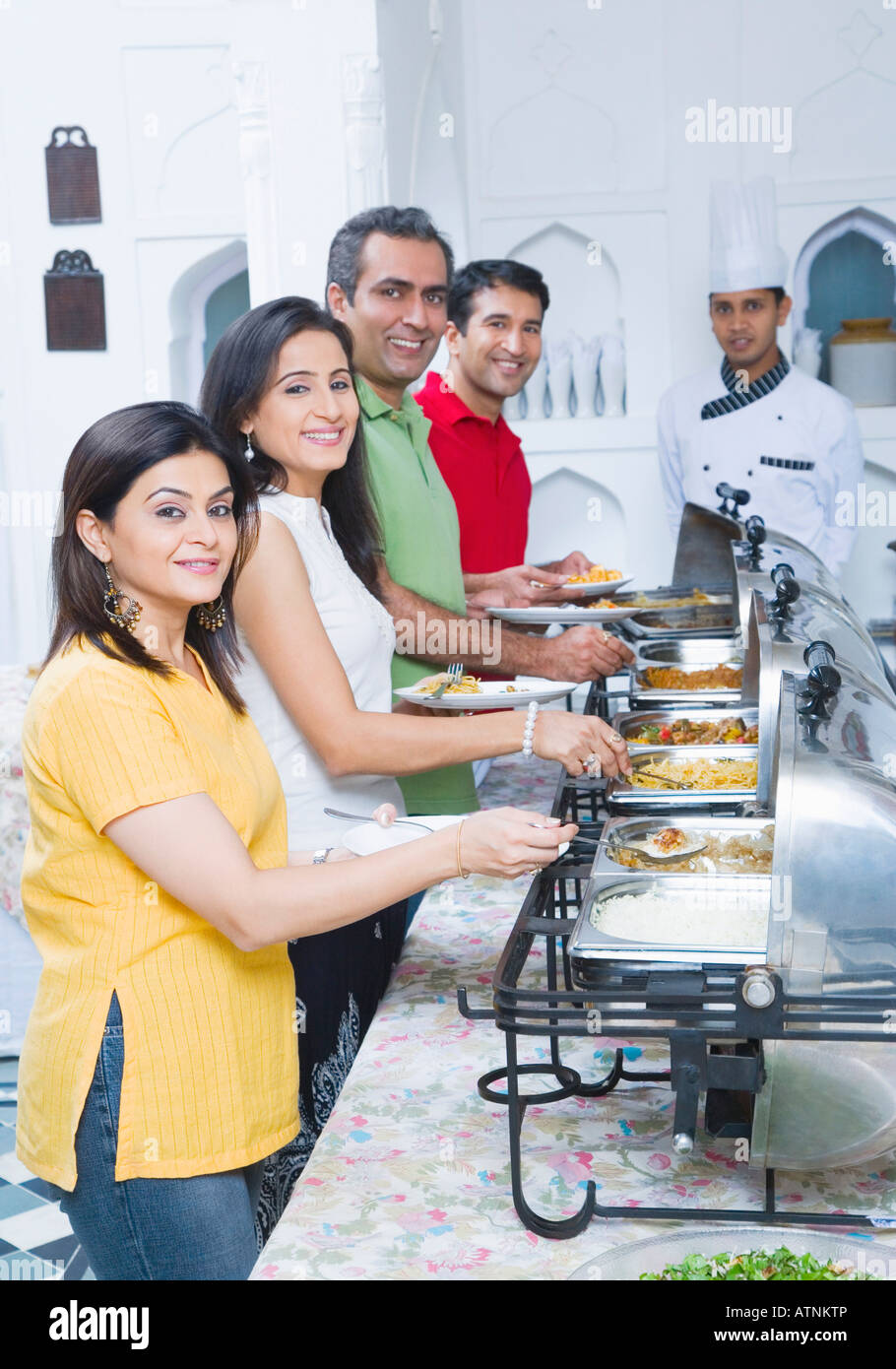 Portrait of two mid adult couples having lunch with a chef standing in ...