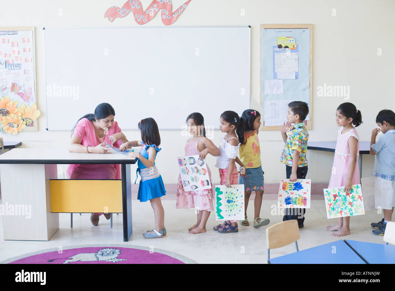 Teacher checking drawings of students in a classroom Stock Photo - Alamy
