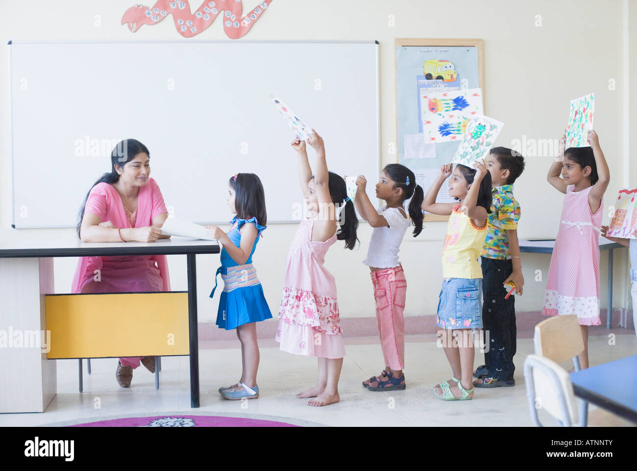 Teacher checking drawings of students in a classroom Stock Photo - Alamy