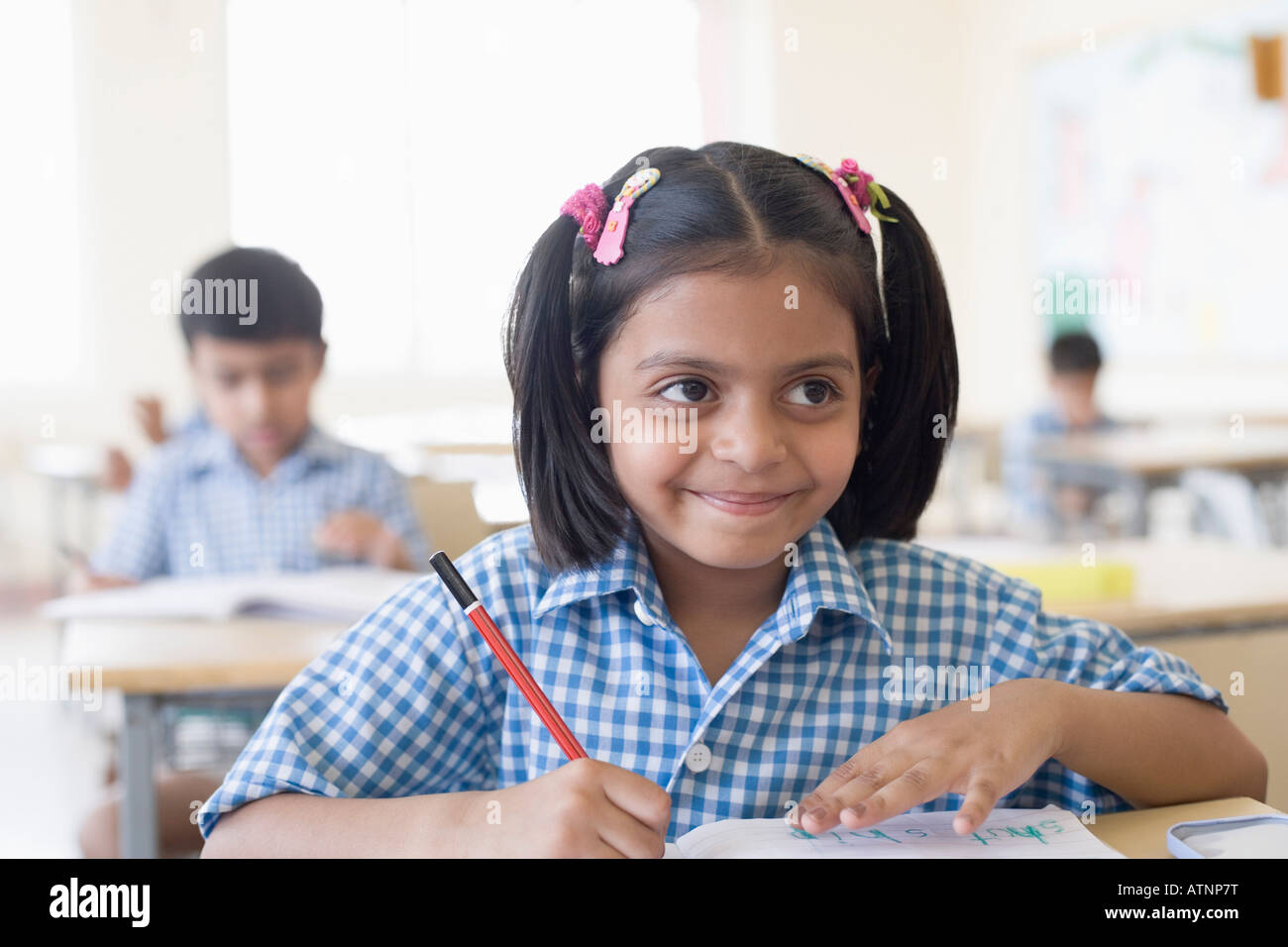 Schoolgirl writing on a notepad in a classroom and smirking Stock Photo ...