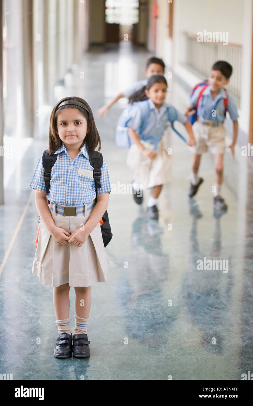 Portrait of a schoolgirl standing in the corridor with three student ...