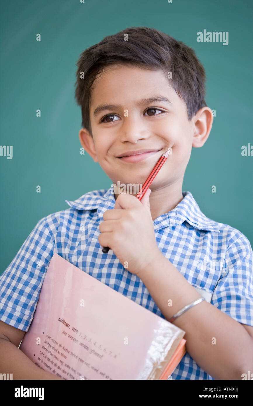 Close-up of a schoolboy holding a pencil and a book in front of a ...