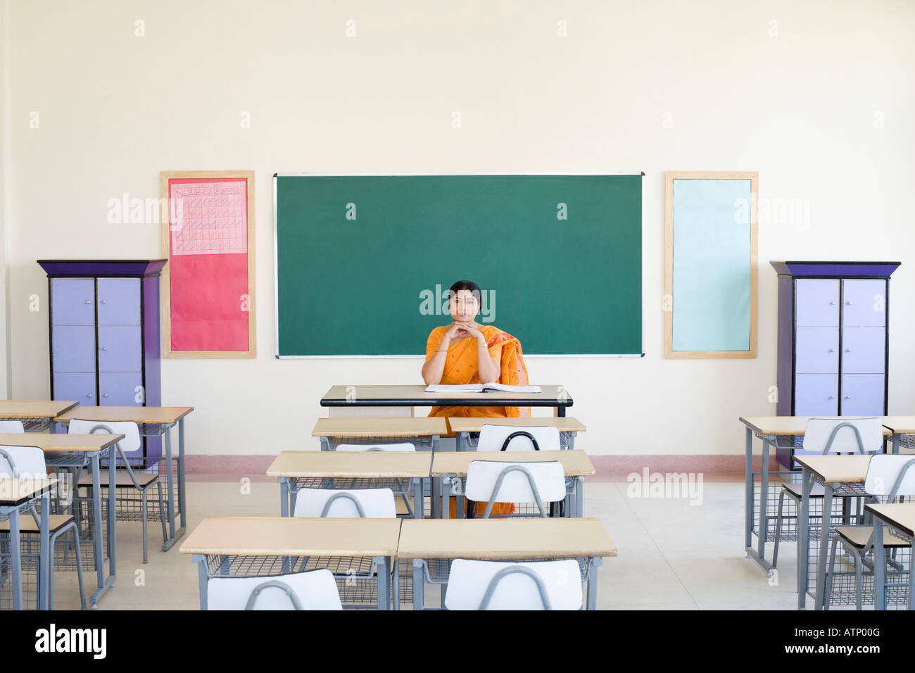 School teacher sitting at a table in a classroom Stock Photo - Alamy