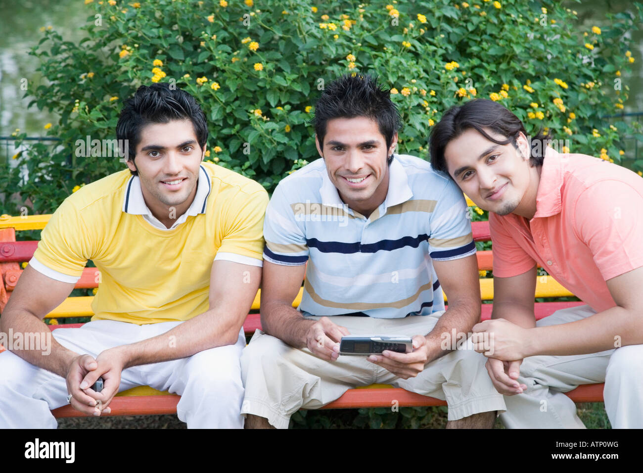 Portrait of a three young men sitting on the bench and smiling Stock ...