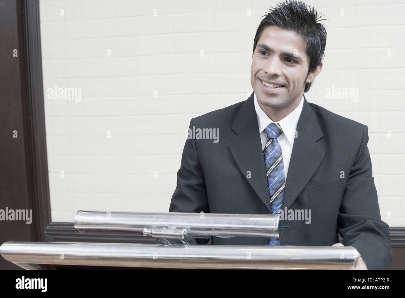 Businessman standing at a lectern and smiling Stock Photo - Alamy