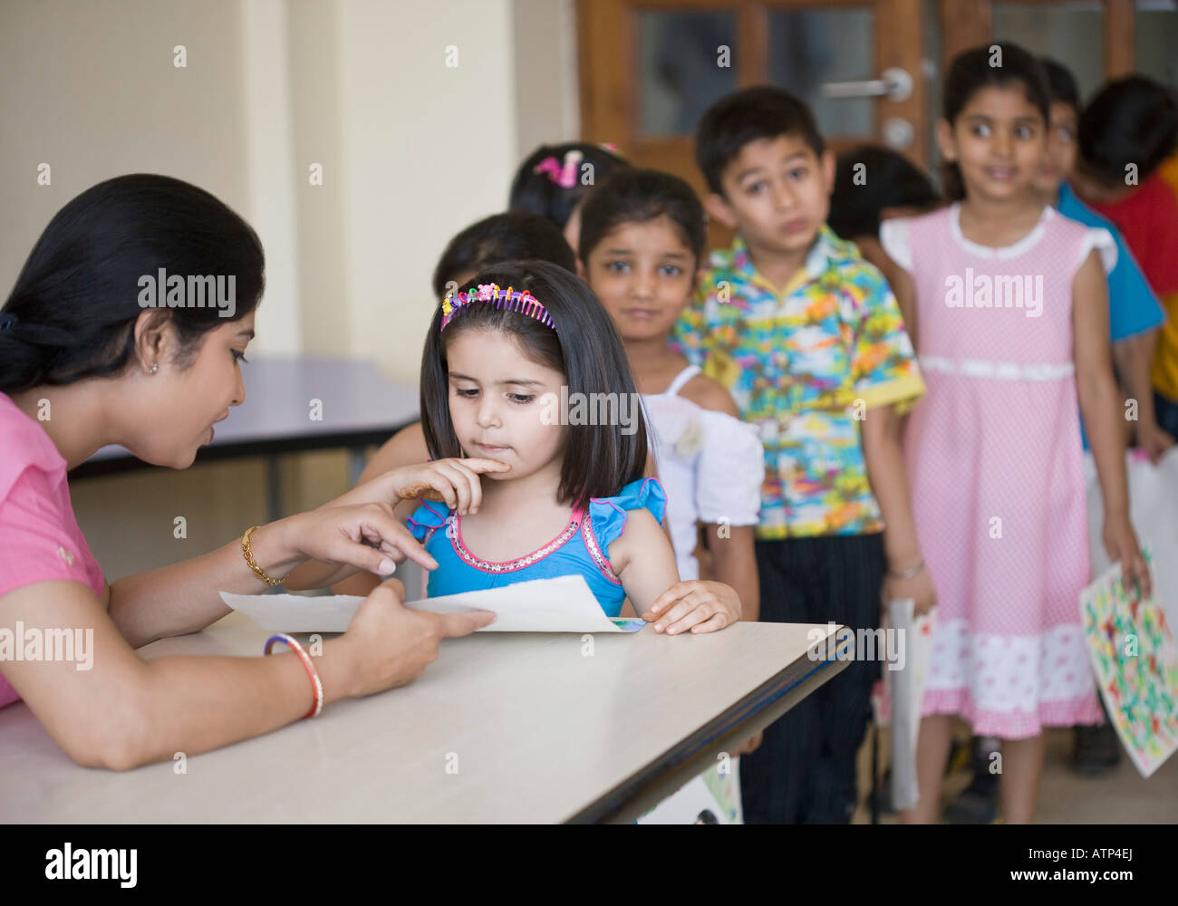 Teacher checking drawings of students in a classroom Stock Photo - Alamy