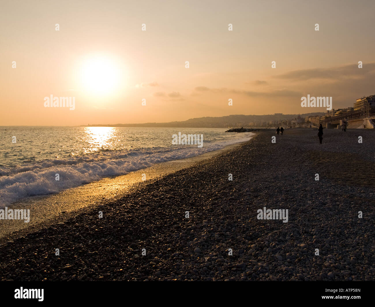 The sun sets on the pebble beach at Nice, France Stock Photo - Alamy
