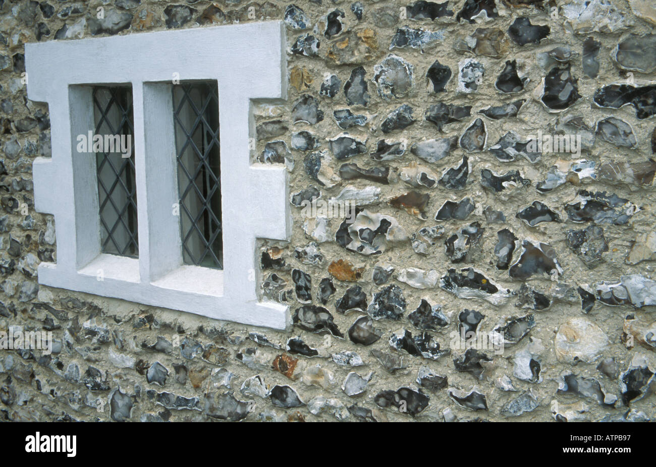 Flints used in a wall of a house with a hand made cut stone window ...