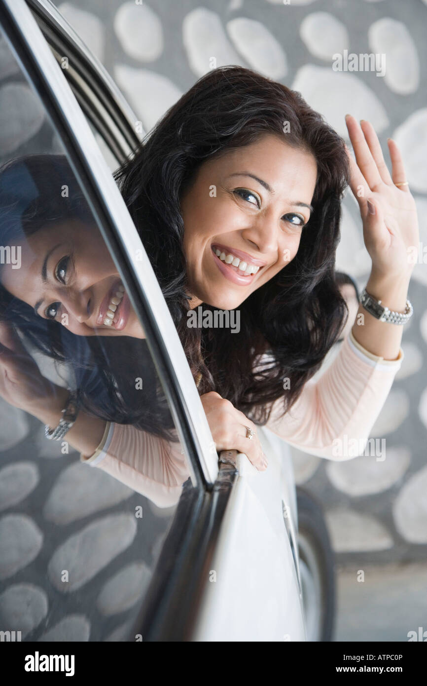 Portrait of a young woman waving her hand from a window of a car Stock ...