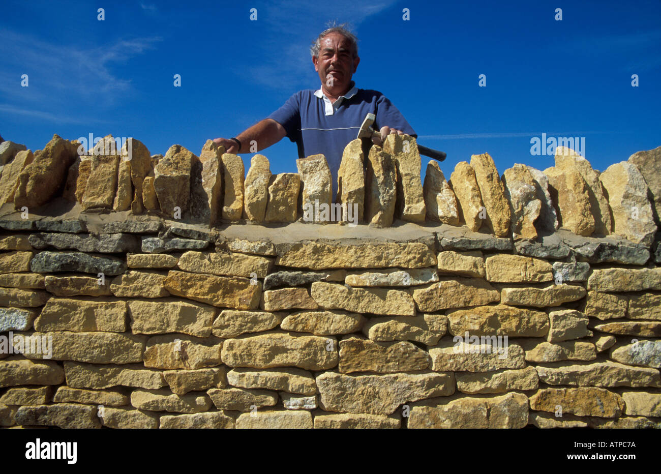 A Traditional Craftsman Building A Dry Stone Wall In The Cotswolds From