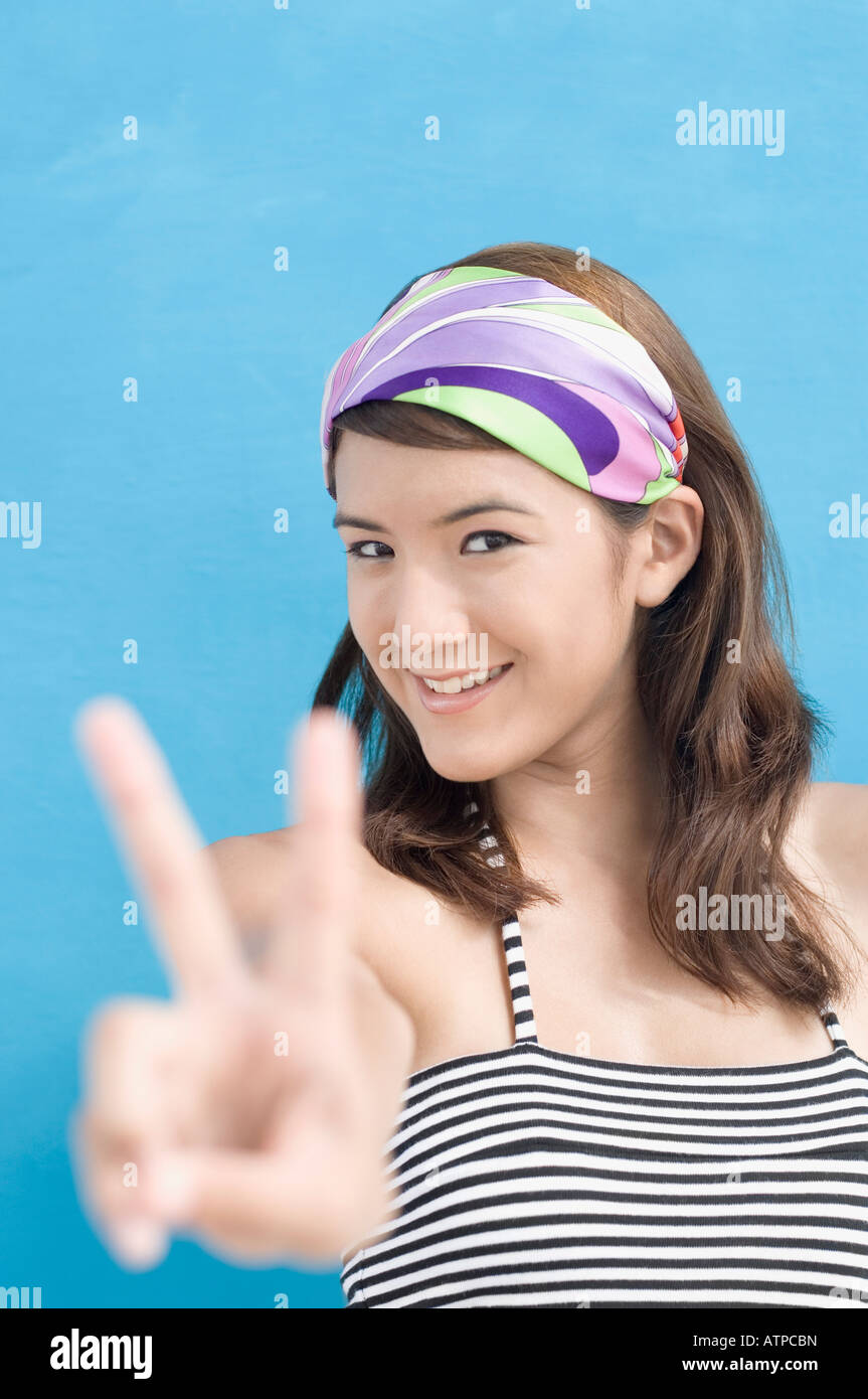 Portrait of a young woman showing a peace sign Stock Photo - Alamy