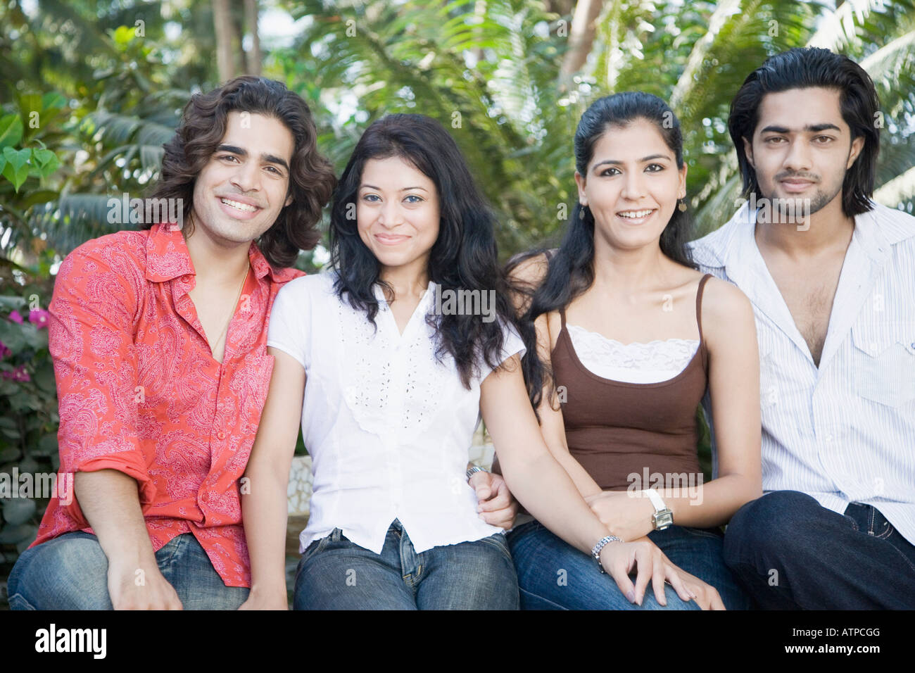 Portrait of two young couples sitting on a ledge and smiling Stock ...