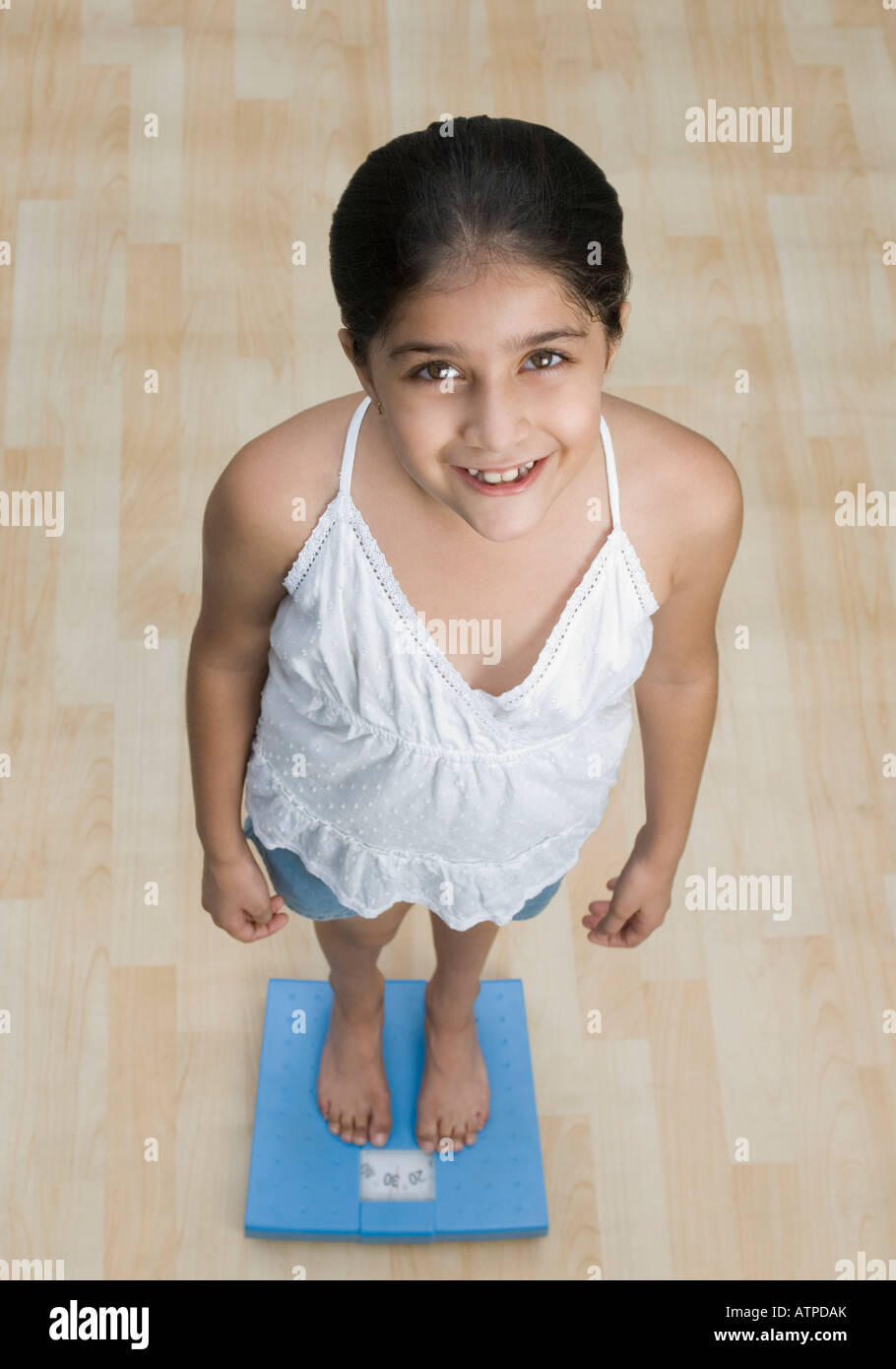 High angle view of a girl standing on a weighing scale and smiling ...