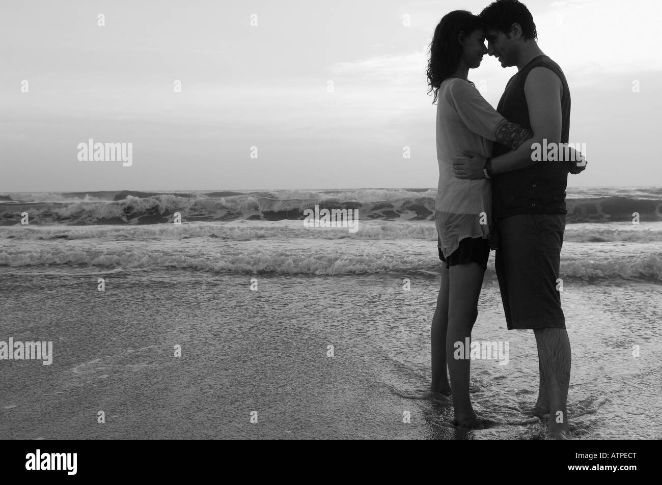 Side Profile Of A Young Couple Standing On The Beach And Embracing Each