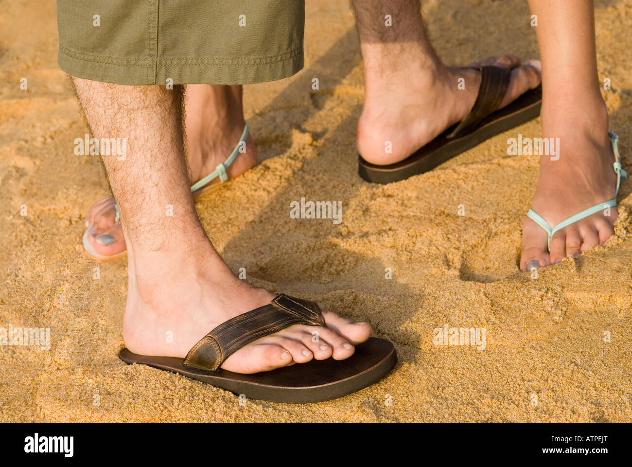 Low section view of a couple standing in sand Stock Photo - Alamy