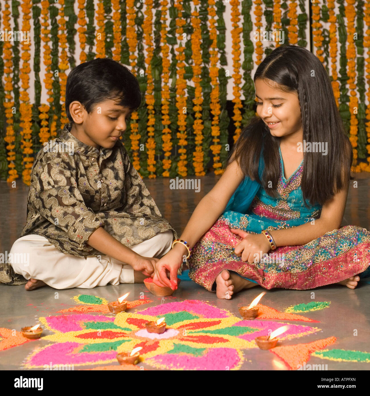 Boy and his sister making rangoli Stock Photo - Alamy