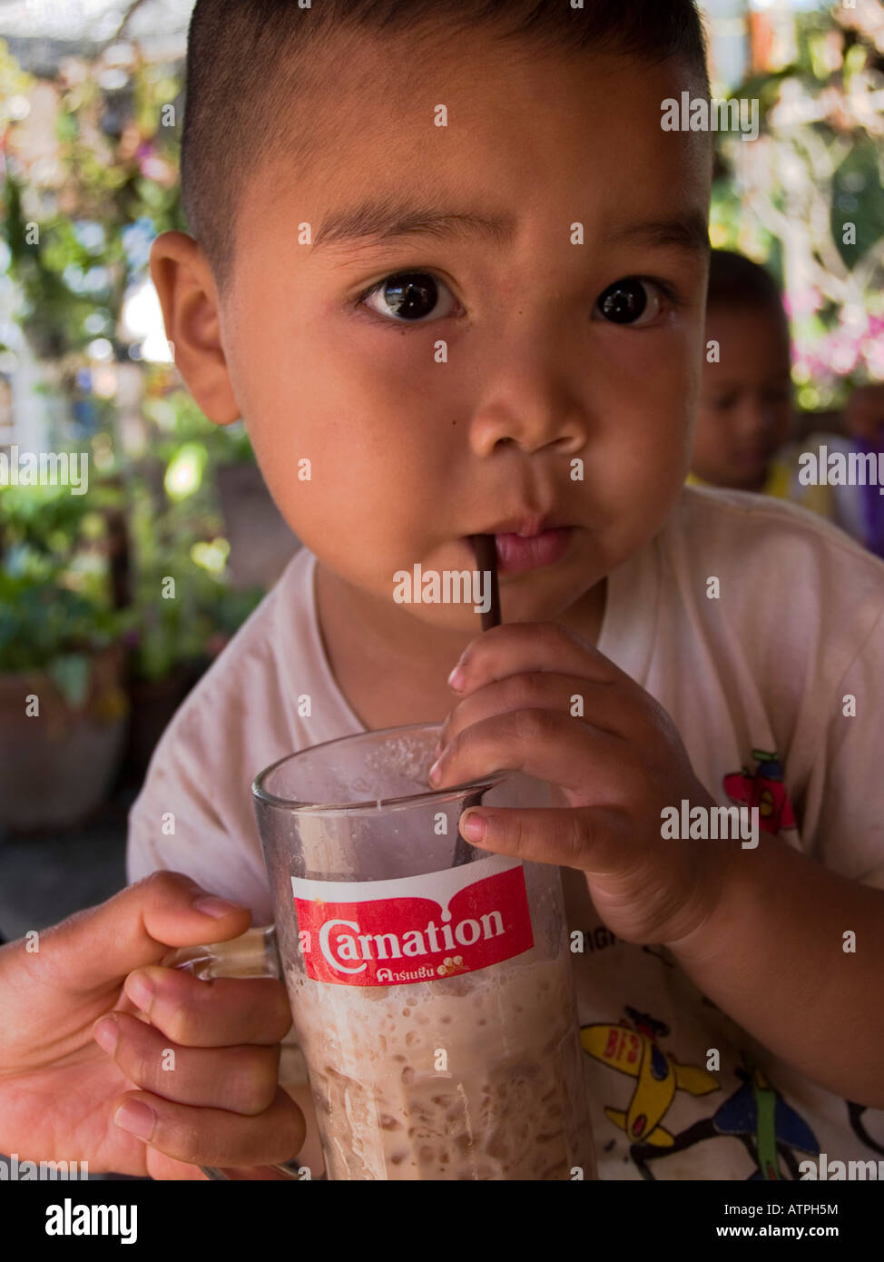Thai boy sipping his Carnation drink Stock Photo - Alamy