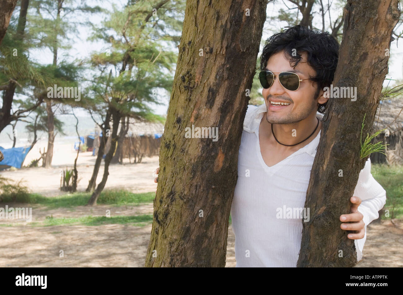 Close-up of a young man standing between two trees Stock Photo - Alamy