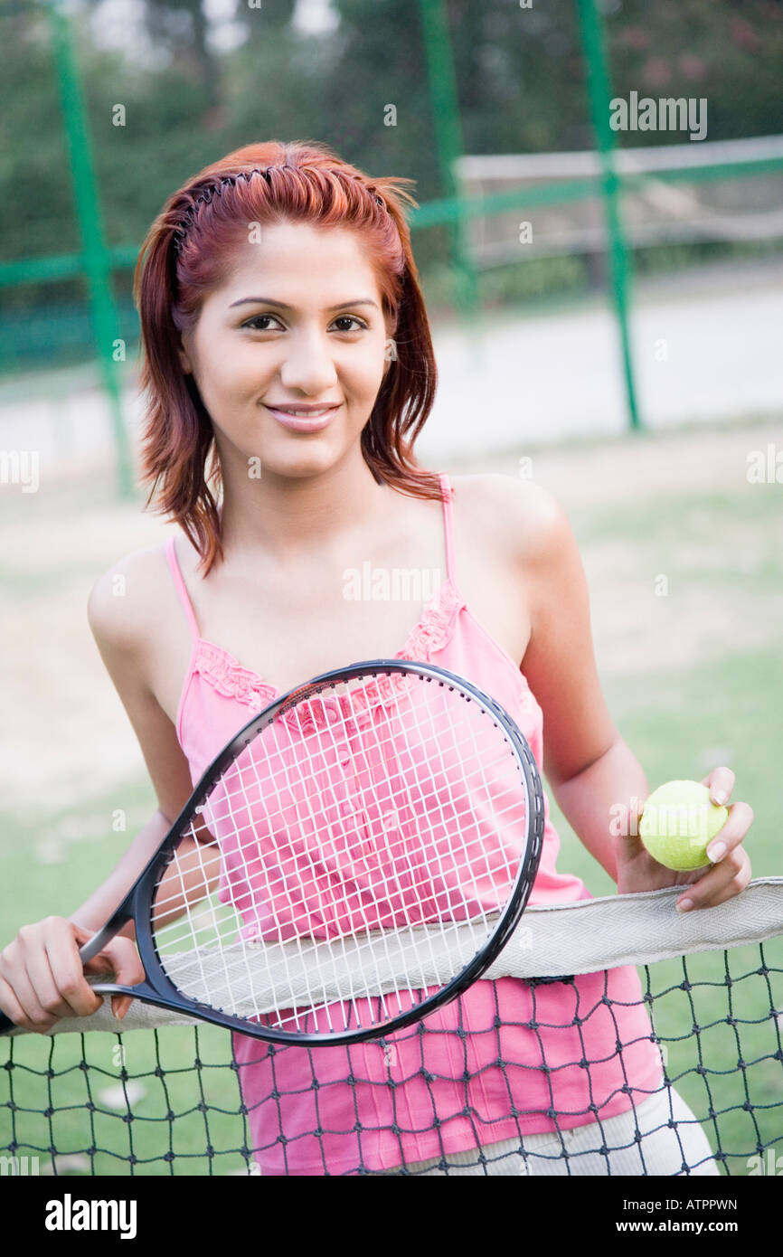 Portrait of a young woman holding a tennis racket and a tennis ball ...