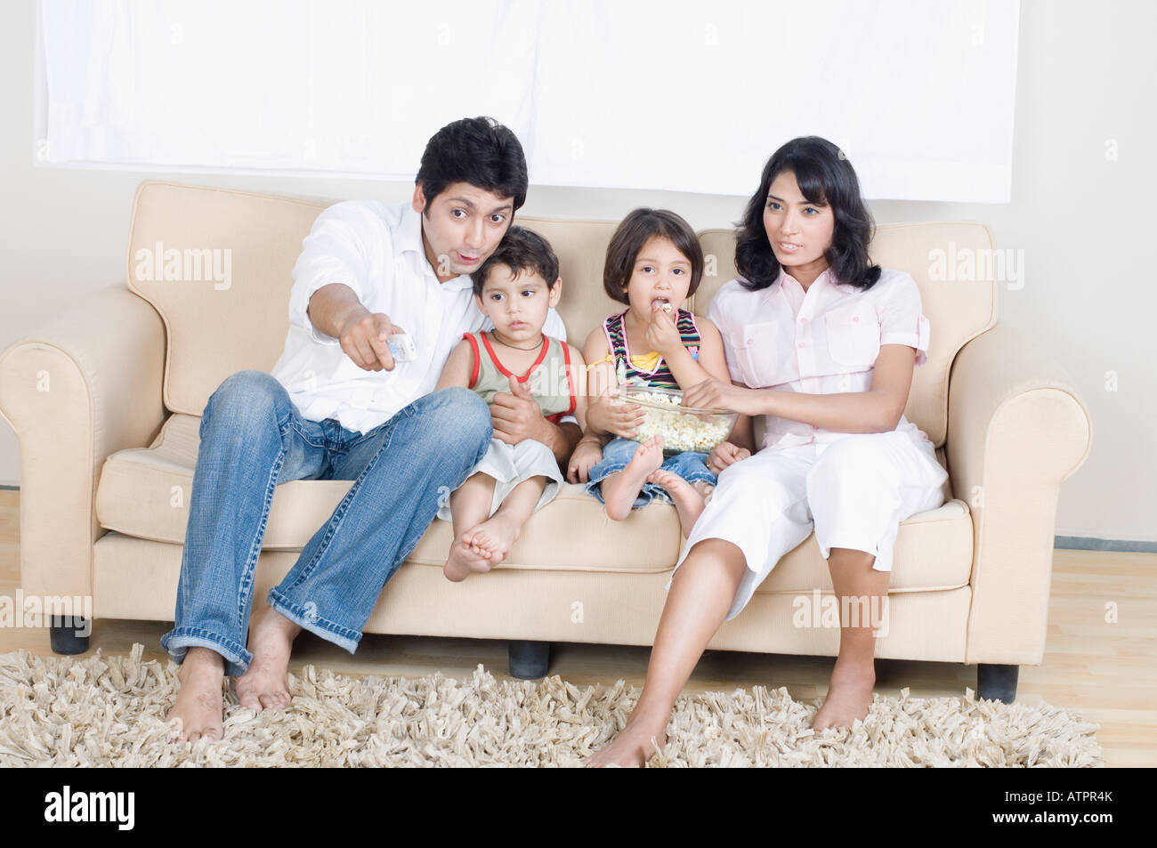 Family sitting on a couch Stock Photo - Alamy