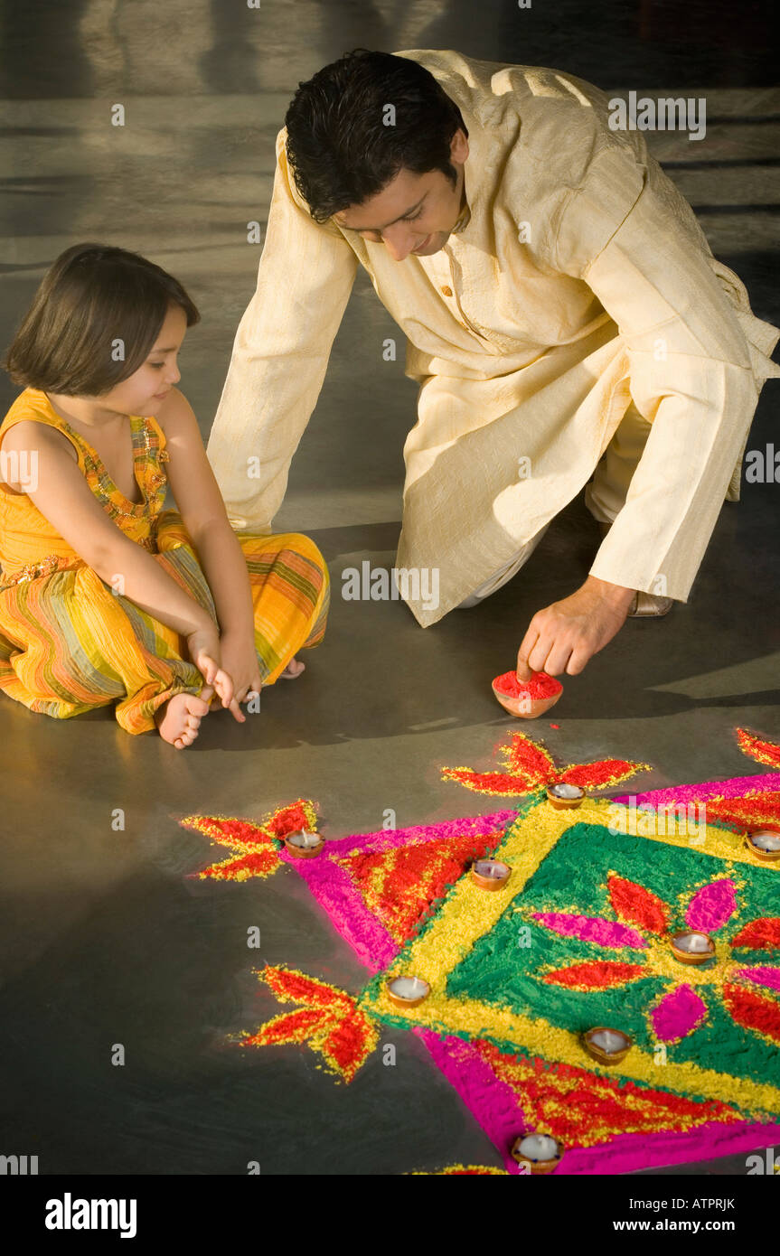 Mid adult man making a rangoli with his daughter Stock Photo - Alamy