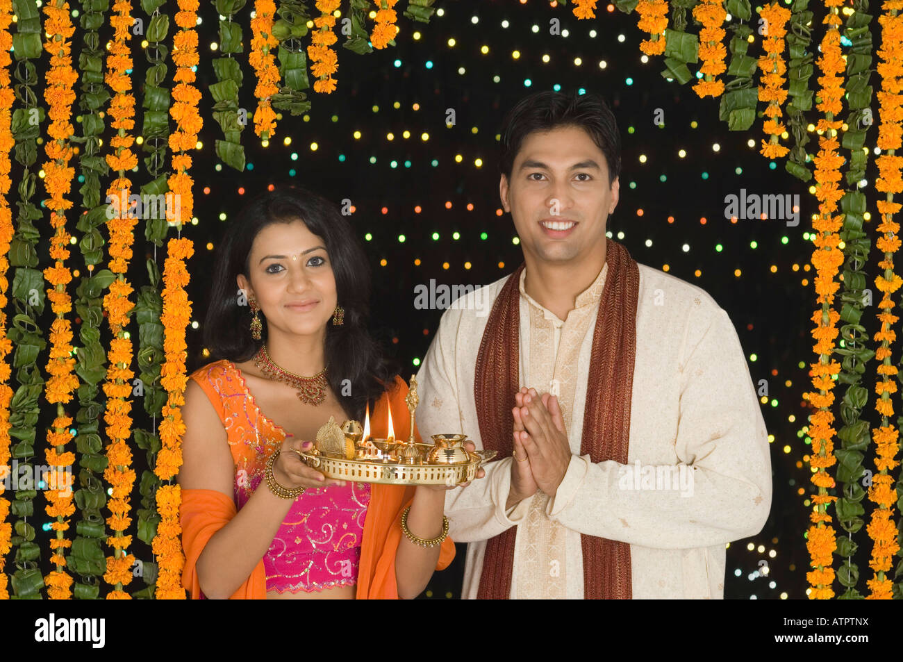 Portrait of a young woman holding a diwali thali with a young man ...