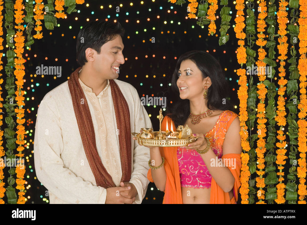 Young woman holding a diwali thali with a young man standing beside her ...