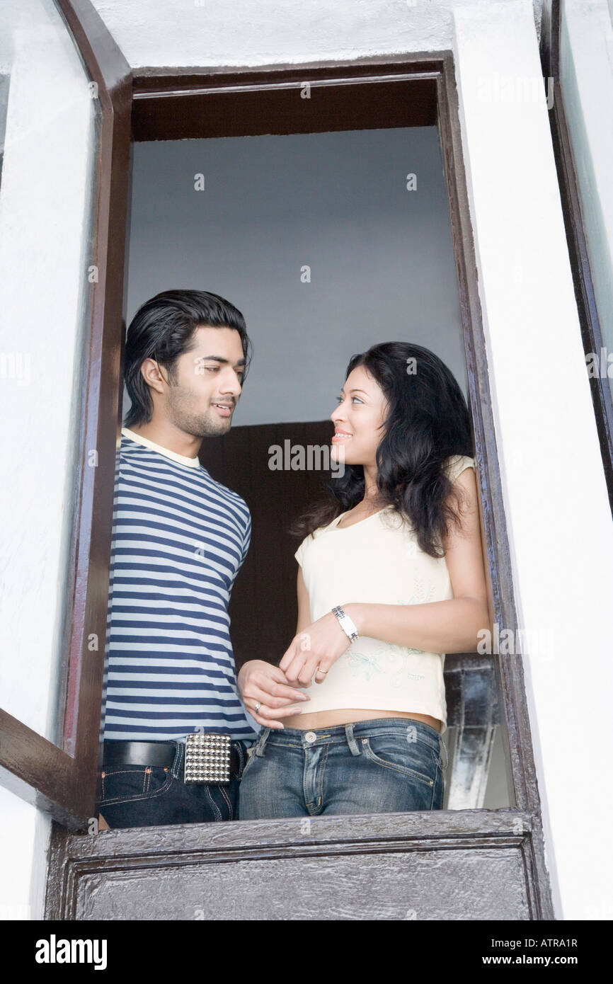 Low angle view of a young couple looking at each other and smiling at a ...