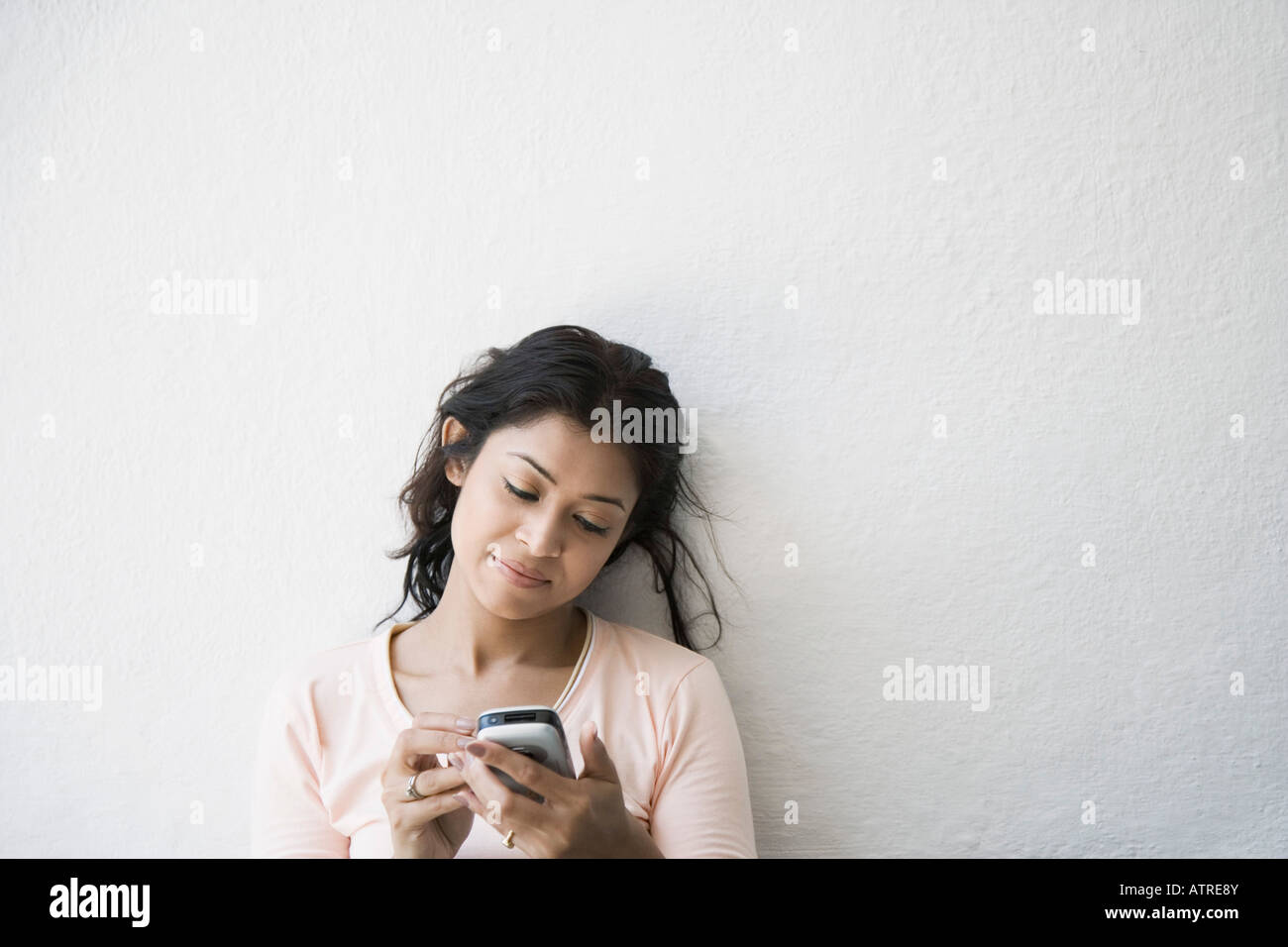 Woman leaning against wall using cell phone hi-res stock photography ...