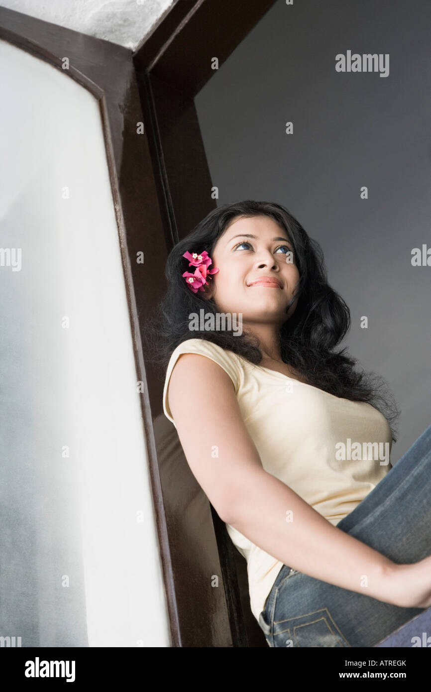 Low angle view of a young woman sitting at the ledge of a window Stock ...