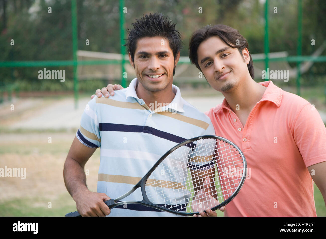 Standing holding smiling tennis racket arm around hi-res stock ...