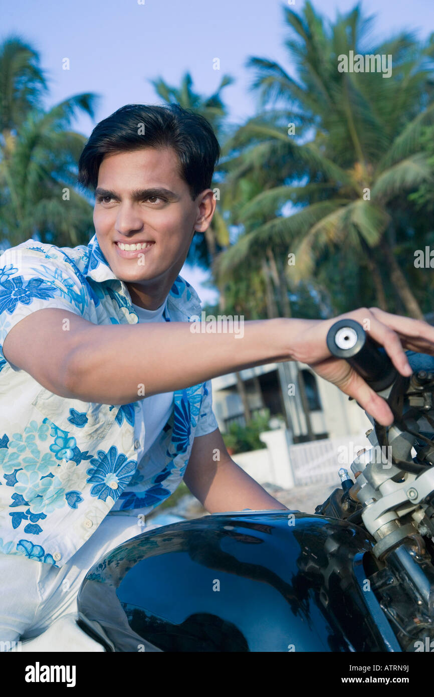 Young man sitting on a motorcycle and smiling Stock Photo - Alamy