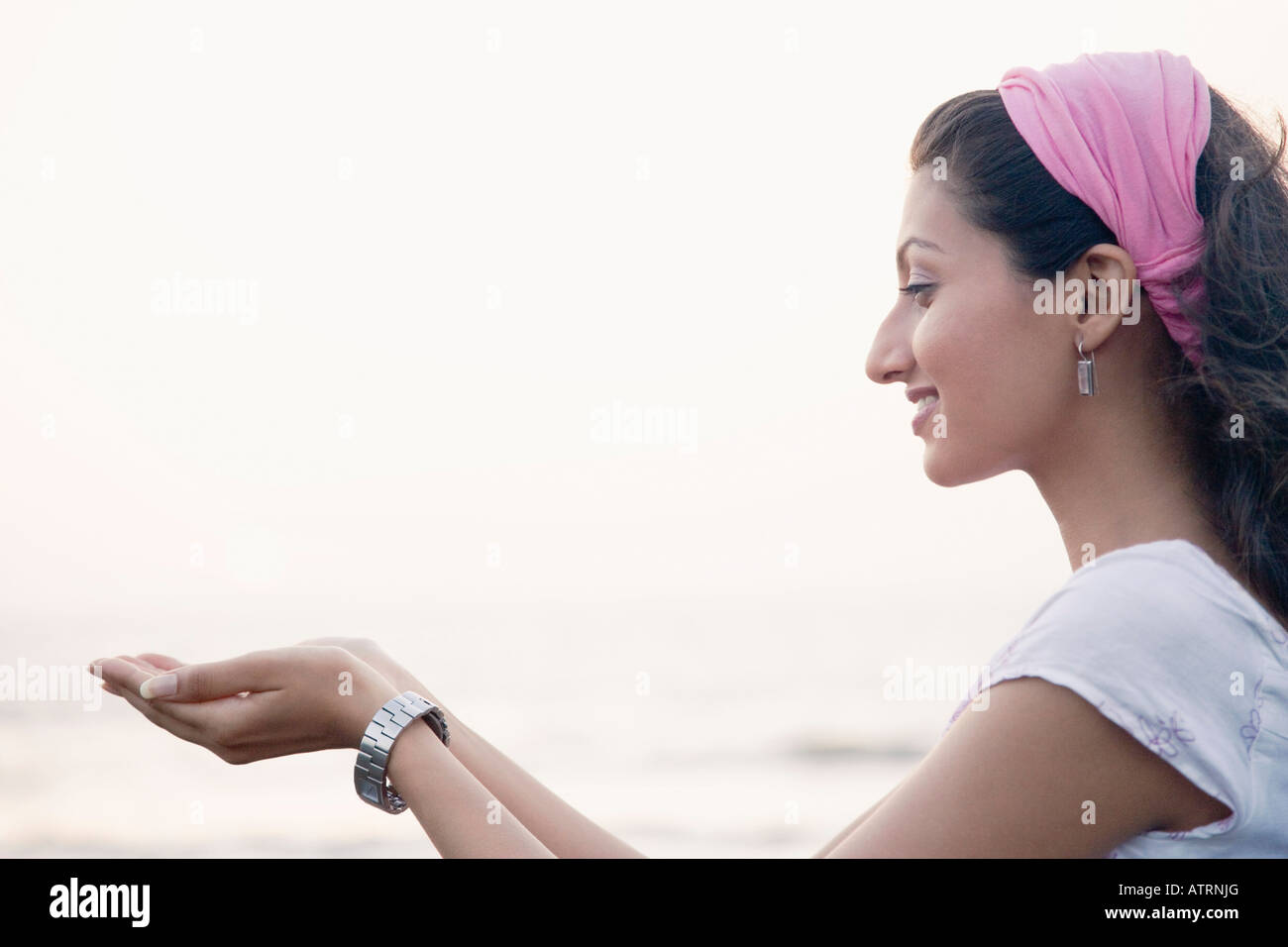 Side profile of a young woman smiling with her hands cupped Stock Photo ...