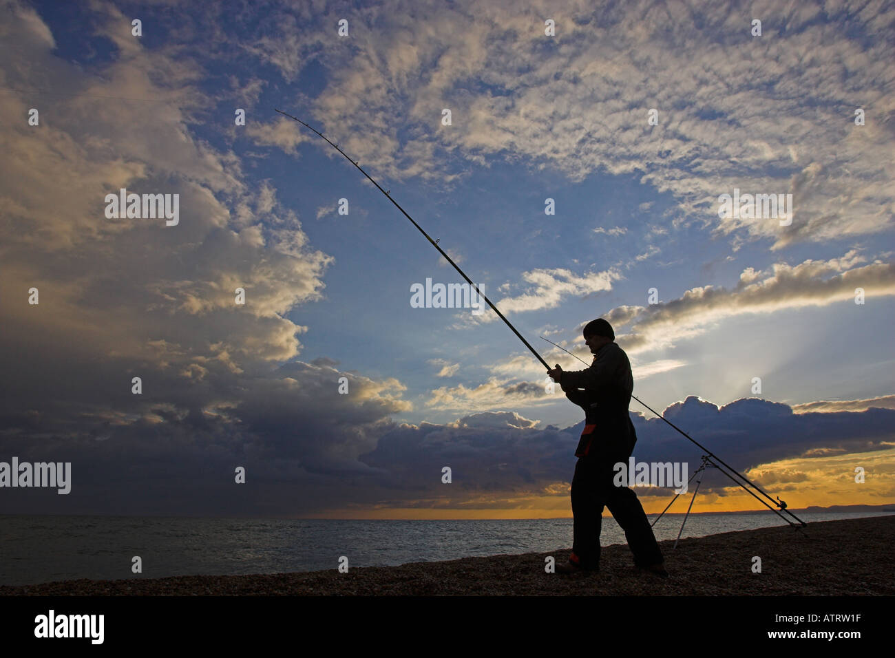 Beach fishing at sunset Stock Photo - Alamy