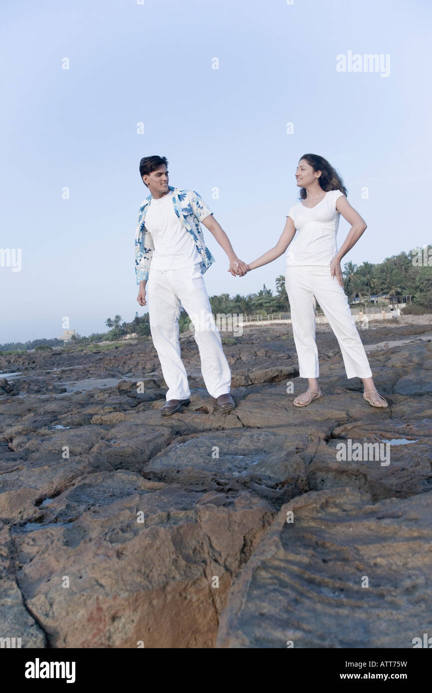 Young couple standing on rocks and holding their hands Stock Photo - Alamy