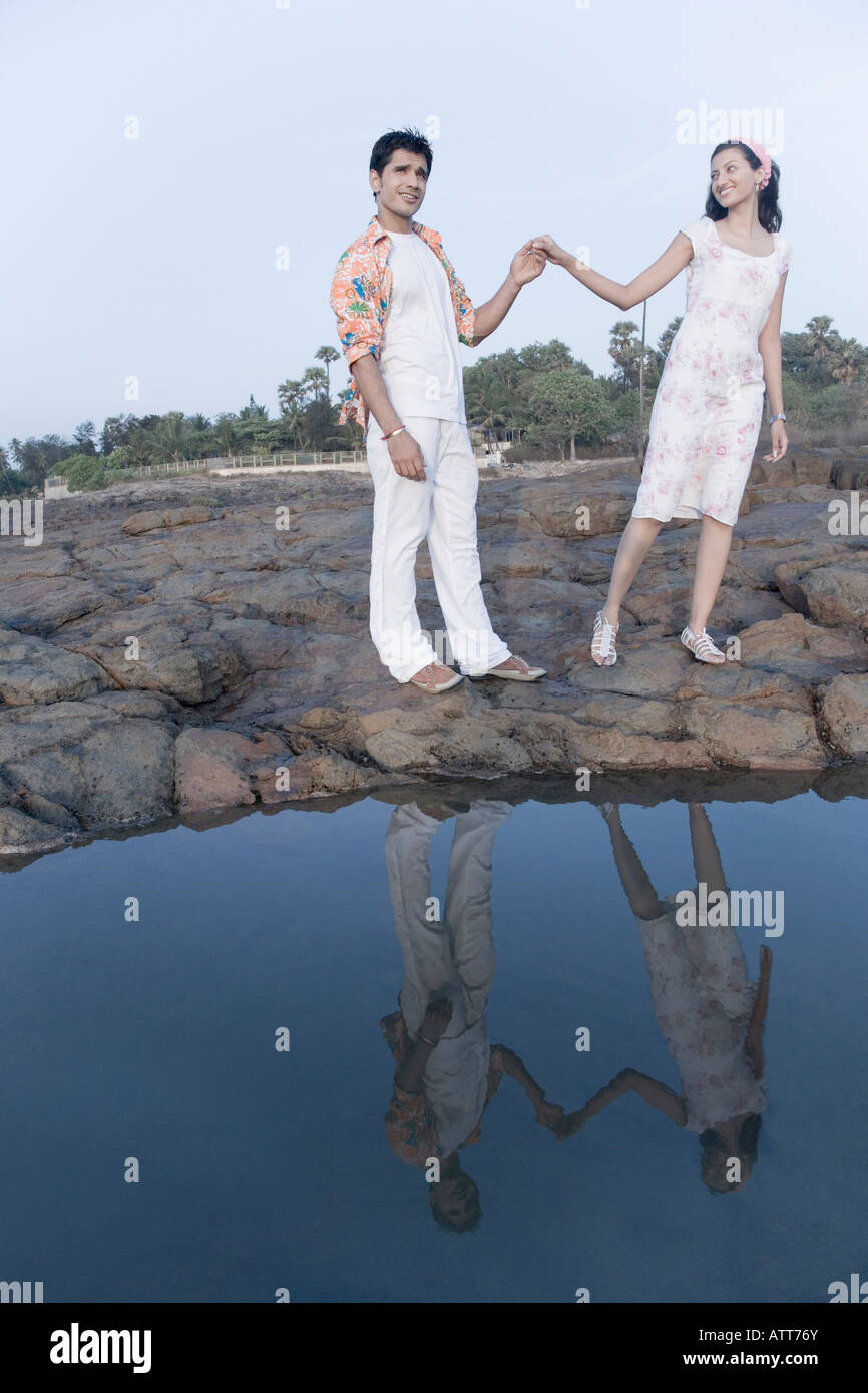 Young couple standing on rocks and holding their hands Stock Photo - Alamy