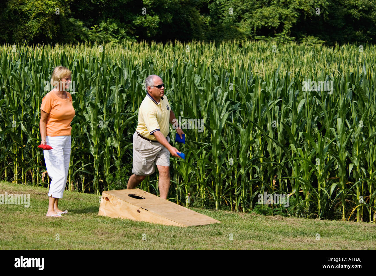 Man and Woman Playing the Game of Cornhole beside Field of Corn ...