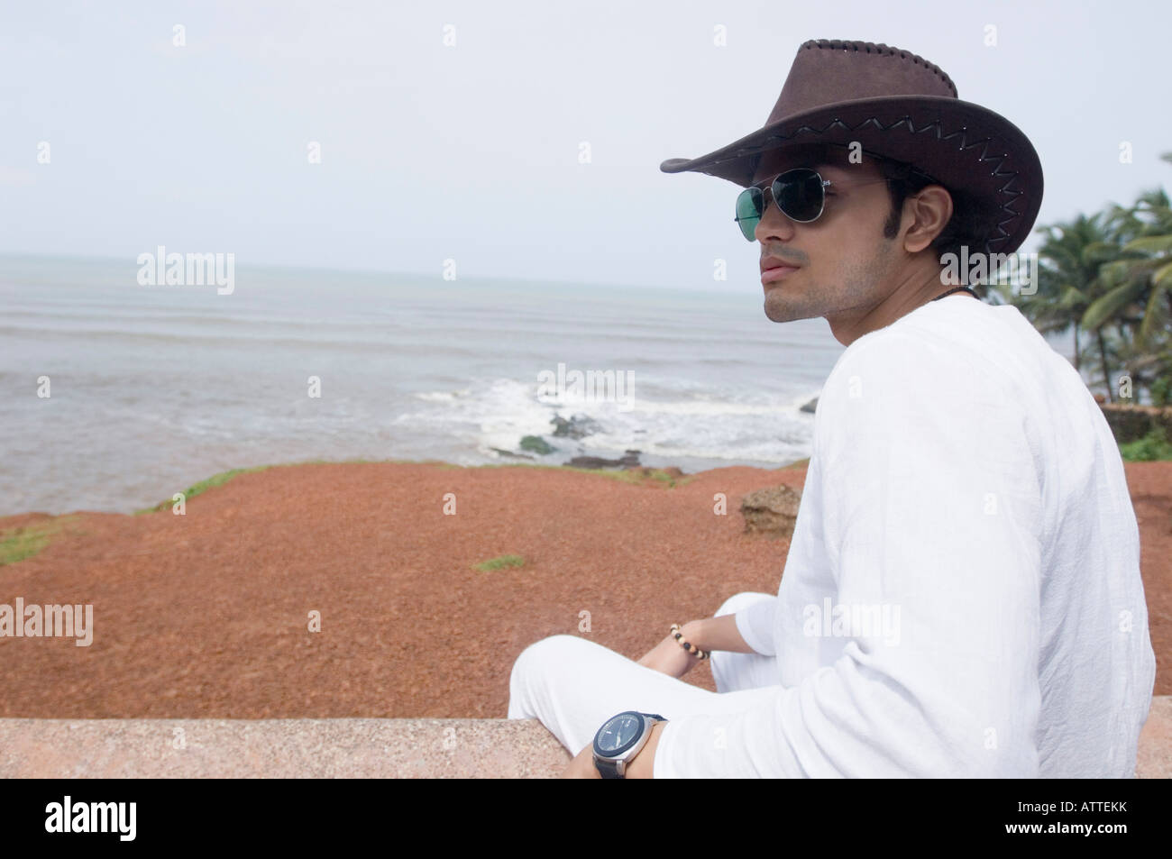 Side profile of a young man sitting on a ledge Stock Photo - Alamy