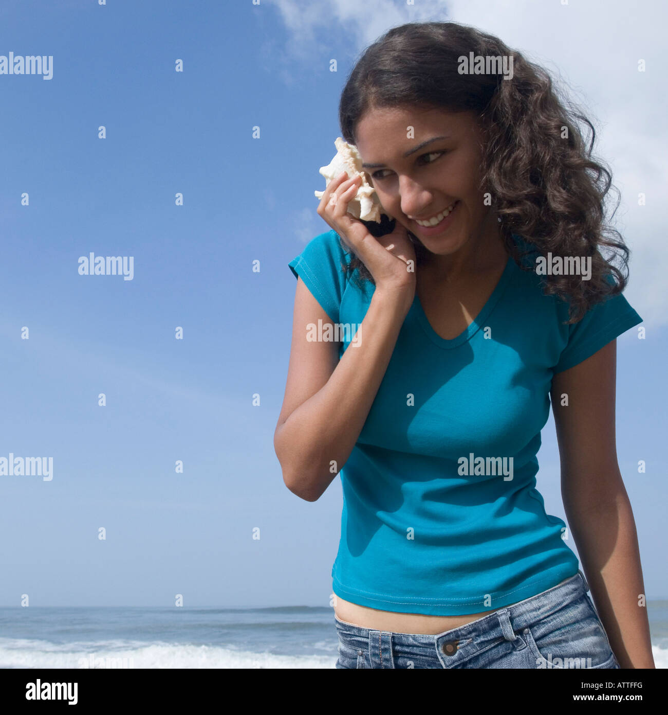 Young woman holding a conch shell close to her ear Stock Photo - Alamy