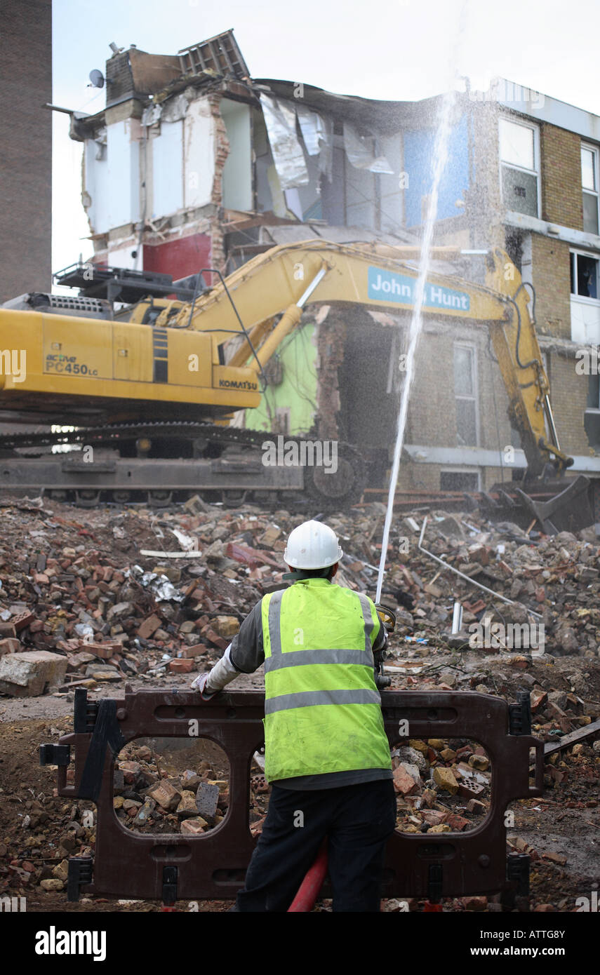A construction worker dampens down dust with a water hose during the ...